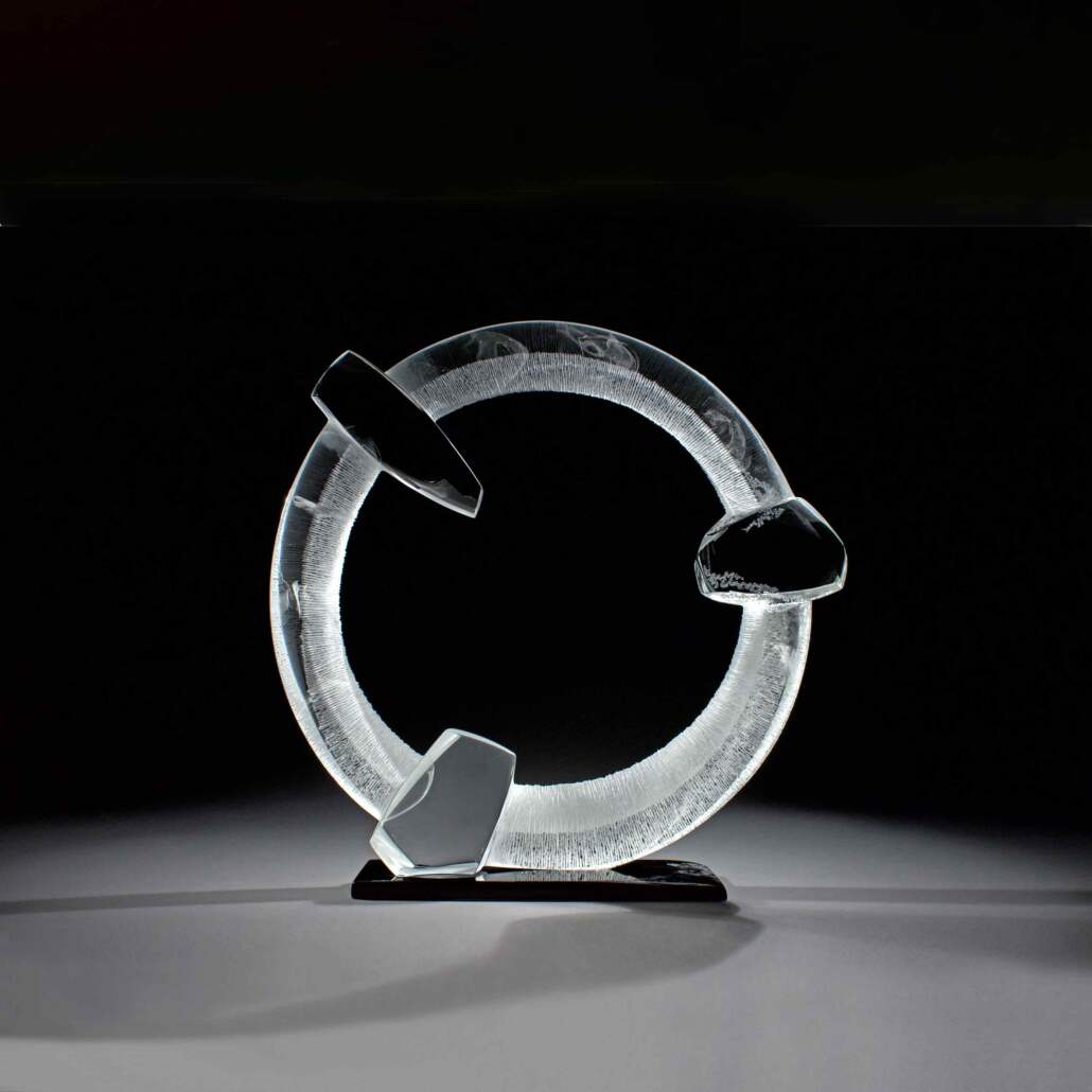 Circular glass sculpture with 3 intersecting transparent blocks